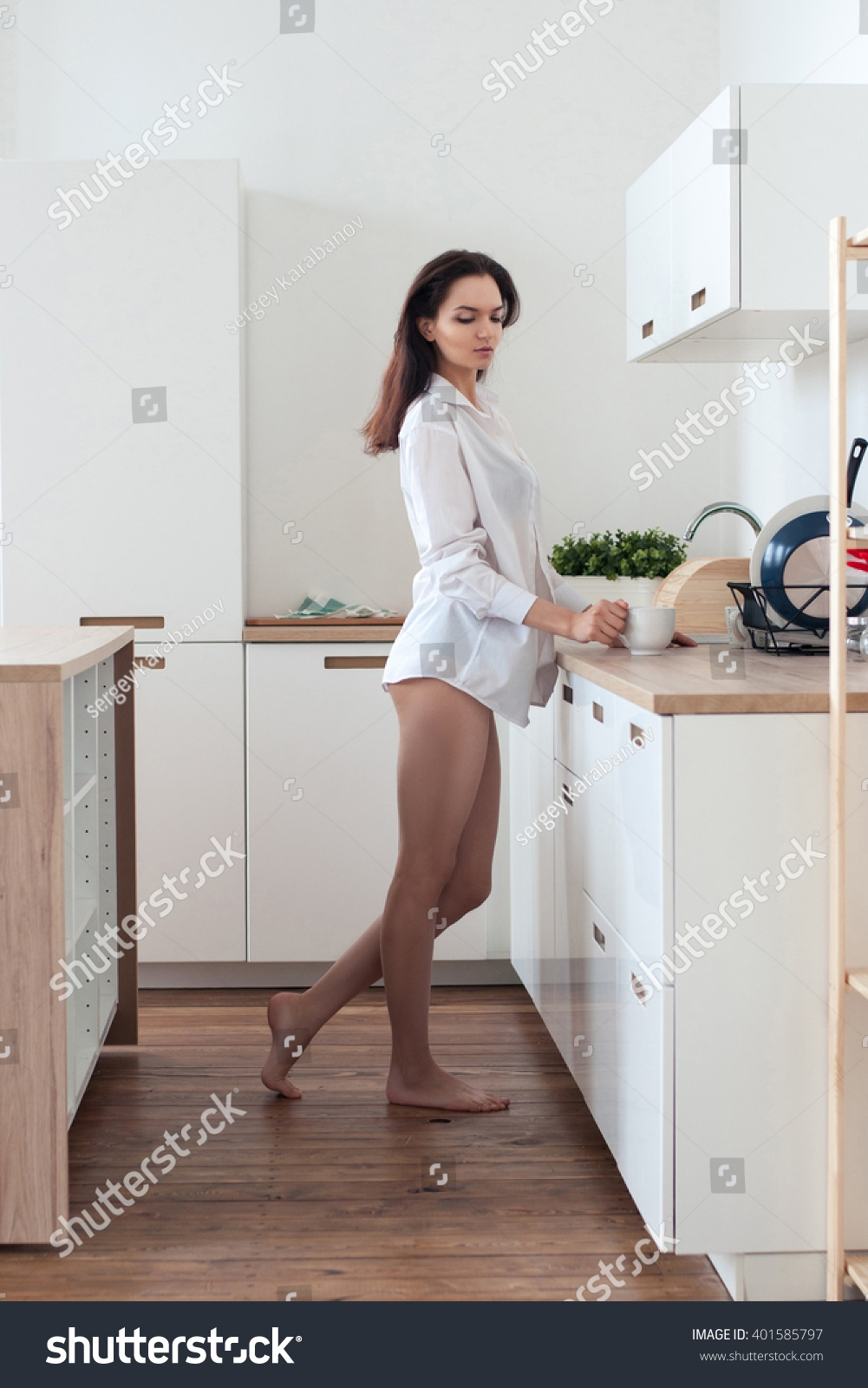 Beautiful Barefoot Female Standing In Kitchen On Wood Floor And Holding