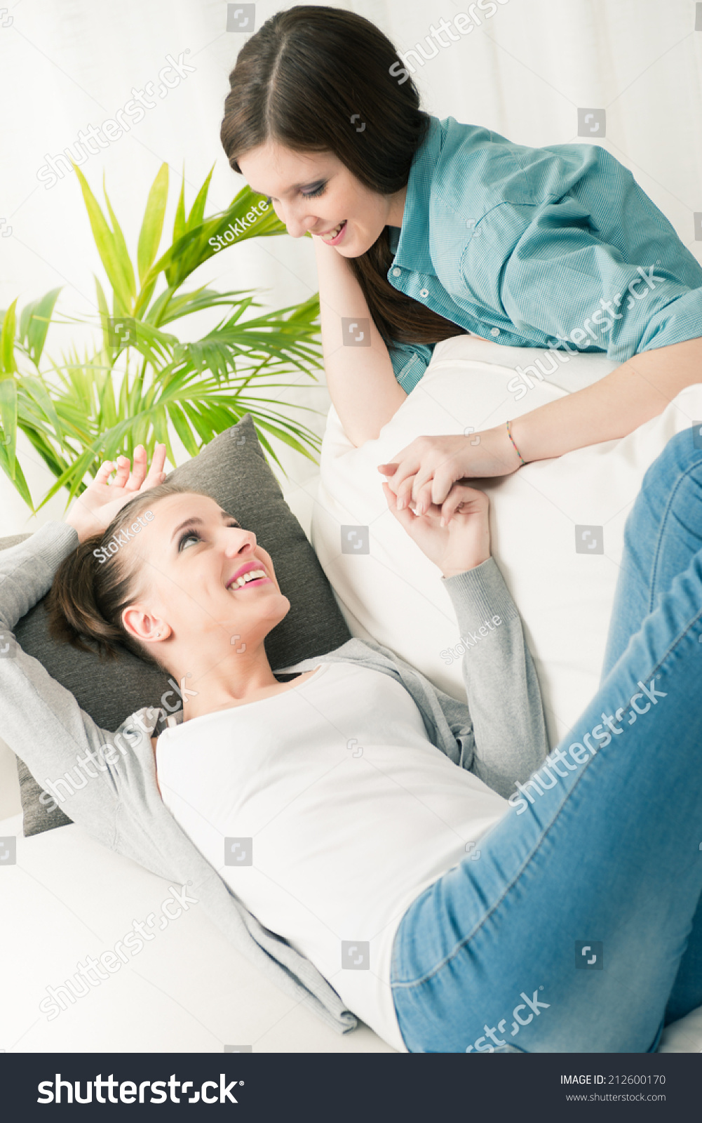 Loving Lesbian Couple Flirting And Holding Hands On The Sofa At Home