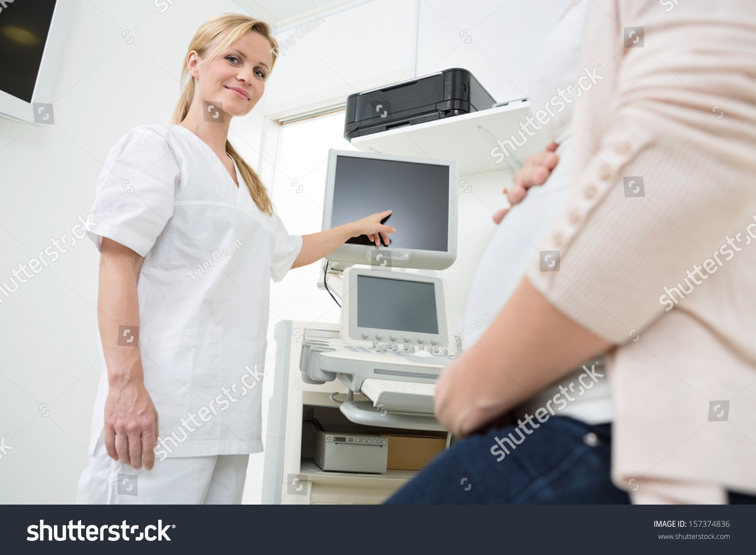Portrait Of Young Gynecologist Showing Ultrasound Scan To Pregnant