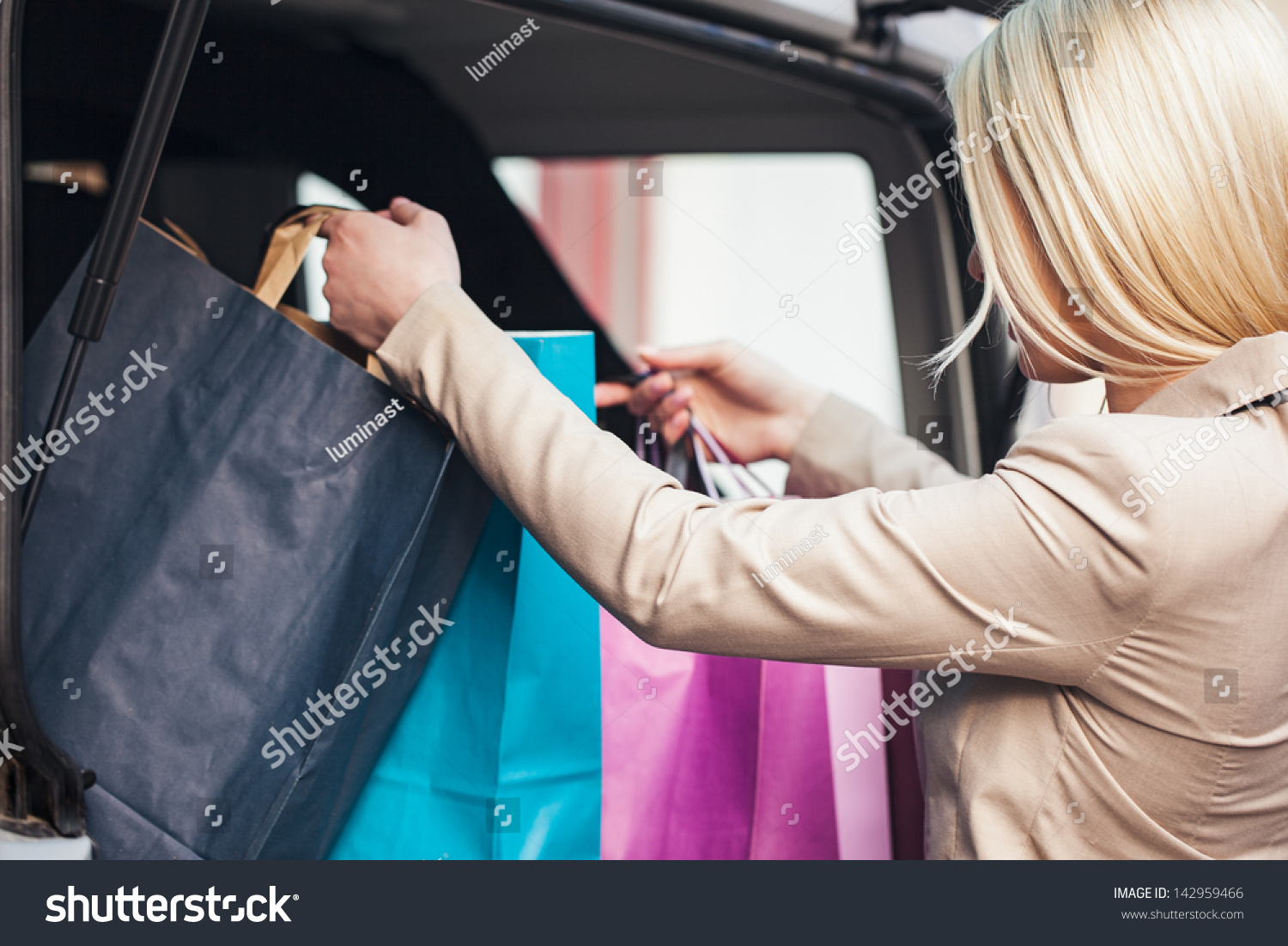 Smiling Caucasian Woman Putting Her Shopping Bags Into The Car Trunk