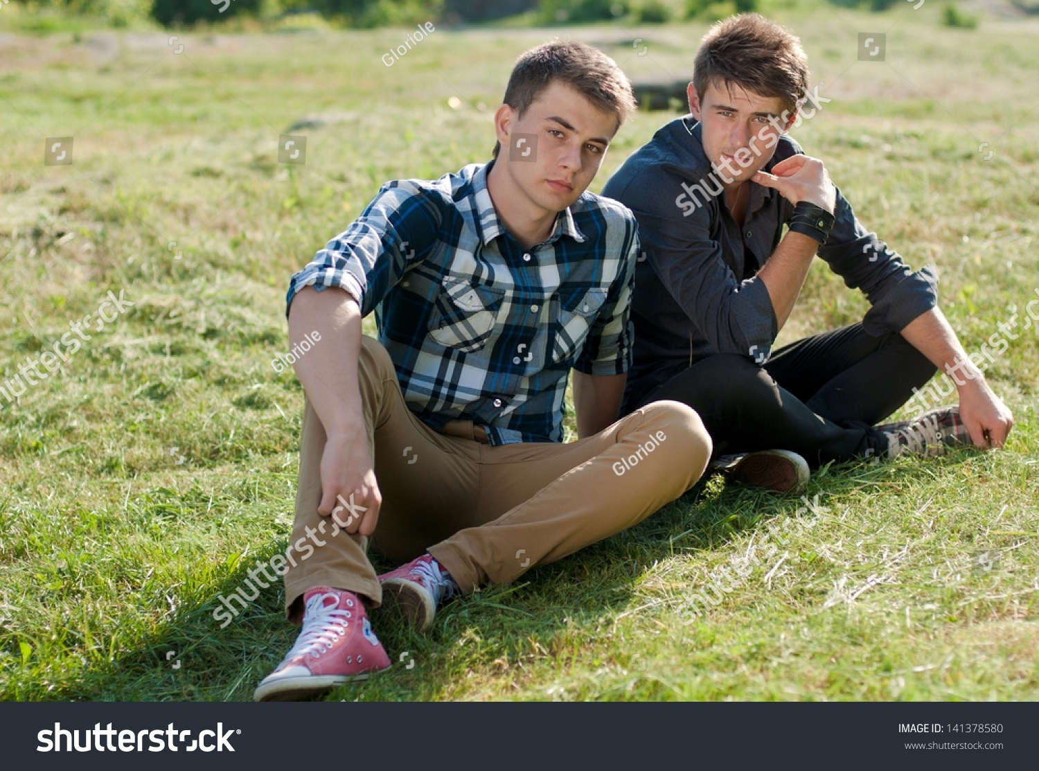 Two Young Men Sitting Together On Green Lawn On Spring Or Summer Day ... Two Young Men Sitting Together On Green Lawn On Spring Or Summer Day ...