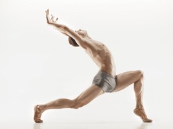 Athletic ballet dancer in a perfect shape performing over the grey ...