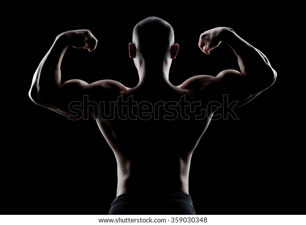 bodybuilder demonstrates biceps back view on a dark background