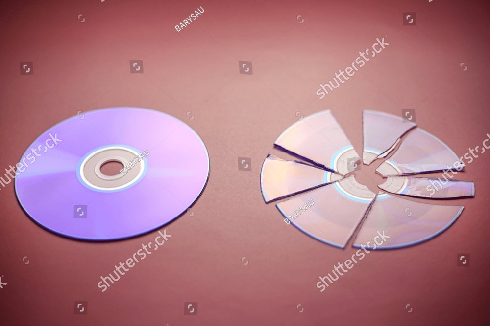 Broken compact disc divided into parts and a whole compact disc close ...