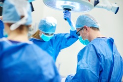 Nurse hand taking surgical instrument for group of surgeons at ...