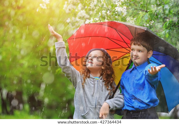Children under umbrella enjoy to spring rain outdoors. Children under umbrella enjoy to spring rain outdoors.