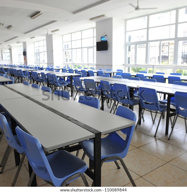 Cafetería de escuela limpia con muchos asientos y mesas vacíos.