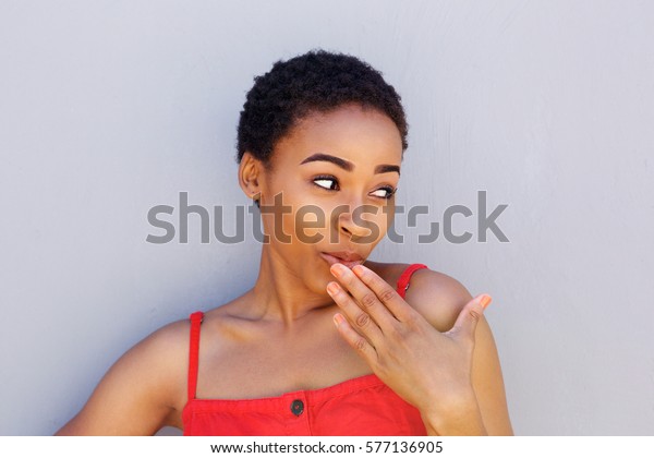 Close up portrait of attractive young black woman hand covering mouth Close up portrait of attractive young black woman hand covering mouth
