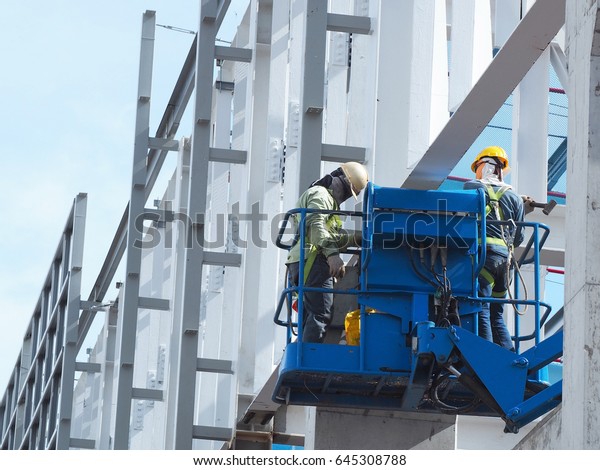 construction worker at construction site using lifting boom machinery