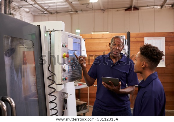 Engineer Training Young Male Apprentice On CNC Machine