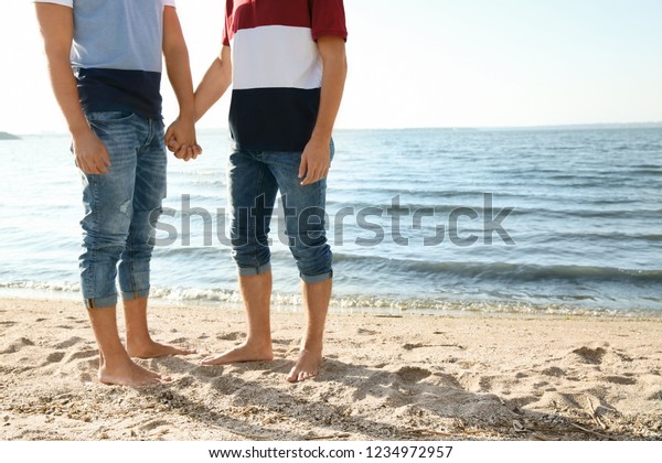 Gay couple standing barefoot on beach. Space for text Gay couple standing barefoot on beach. Space for text
