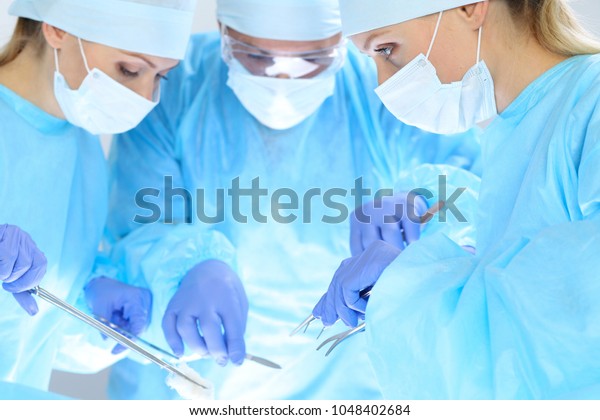 Group of surgeons at work while operating at hospital. Health care and ...
