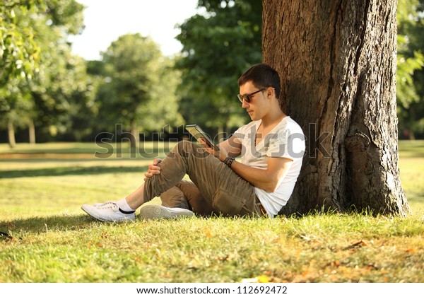 Guy Sitting Beneath Tree Using Tablet库存照片112692472 | Shutterstock