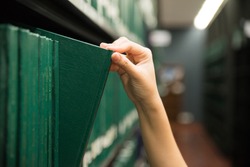 Hand pulling a book off the shelf featuring book, bookcase, and books ...
