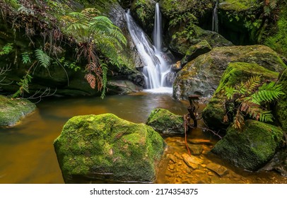 Waterfall flowing into the lake and mossy stones on the rocks in the ...