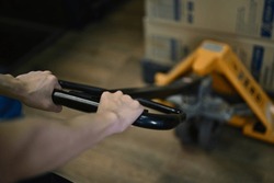 Happy logistics workers loading cardboard boxes onto a pallet truck, a ...