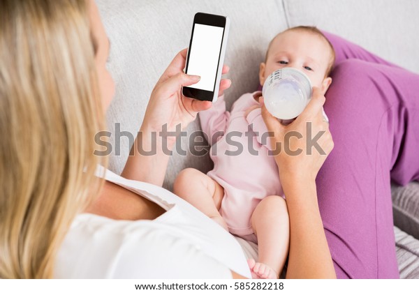 Mother Using Mobile Phone While Feeding Stock Photo 585282218 ...