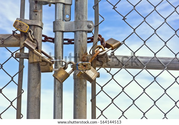Multiple padlocks used on a chain link fence help keep it lock and close.