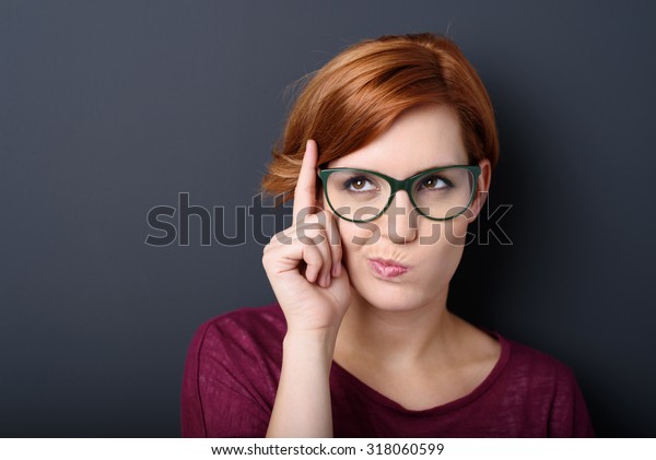 书呆子学术年轻女子戴着怪胎眼镜站在思考,她的手指提出和浓度的鬼脸在幽默的陈规定型描绘,在黑暗的背景下与复制空间 库存照片(立即编辑)318060599