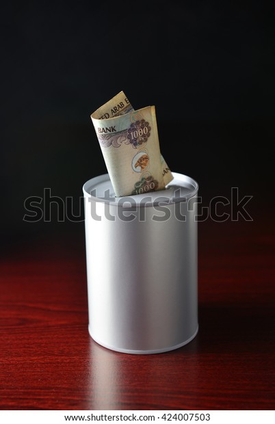 One thousand dirham note inserted in the saving can. Saving tin and UAE ...