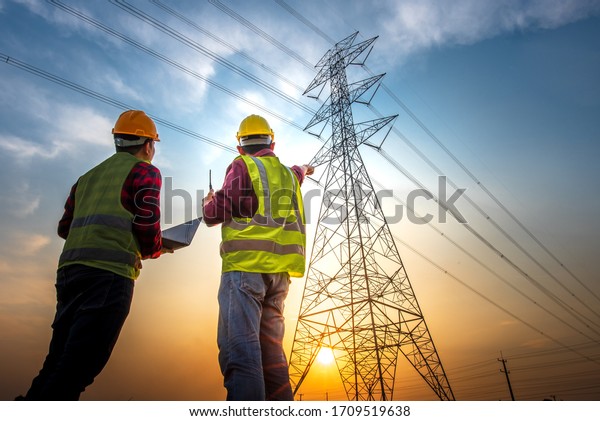Imagen de dos ingenieros eléctricos usando un ordenador portátil parado ...