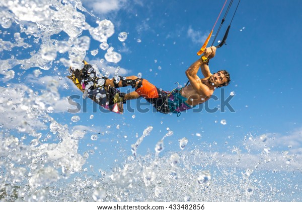 el kiter profesional hace el difícil truco en un bello fondo de spray y ...