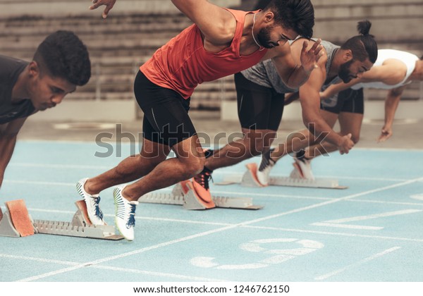 Runners using starting blocks to start the race on running track ...