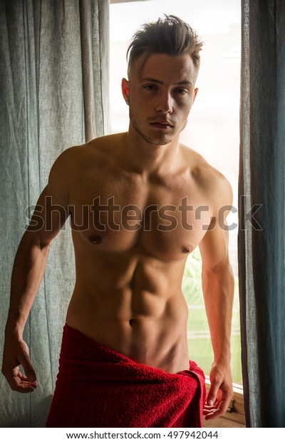 Sexy handsome young man standing shirtless in his bedroom next to ... Sexy handsome young man standing shirtless in his bedroom next to ...