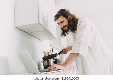 Smiling Jesus Using Laptop While Cooking Stock Photo 1192415503 ...
