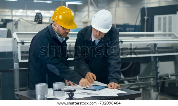Two Engineers Discuss Blueprint While Checking Stock Photo 702098404 ...