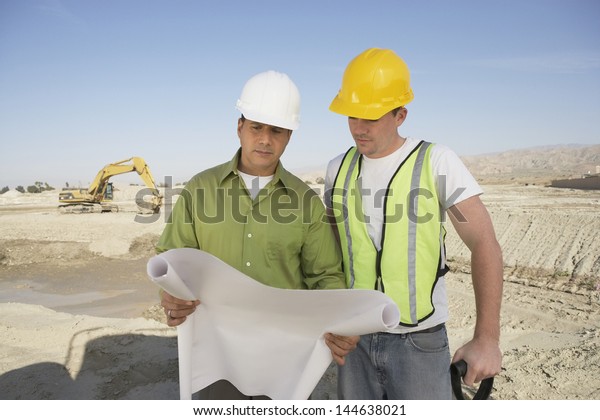 Two Multiethnic Construction Workers Reading Blueprints Stock Photo ...
