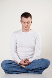 Portrait of a healthy young sportsman meditating in lotus pose, a ...