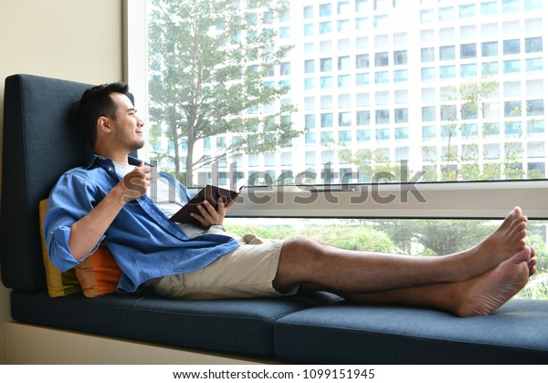 Young Man Drinking Coffee While Sitting Stock Photo (Edit Now) 1099151945 Young Man Drinking Coffee While Sitting Stock Photo (Edit Now) 1099151945