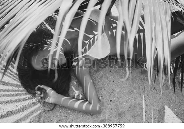 Young Sexy Woman Laying On Sand Beach Under Palm Tree Leaf Artistic